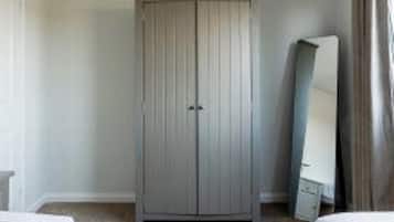 Quarto com guarda-roupa, cama e espelho.