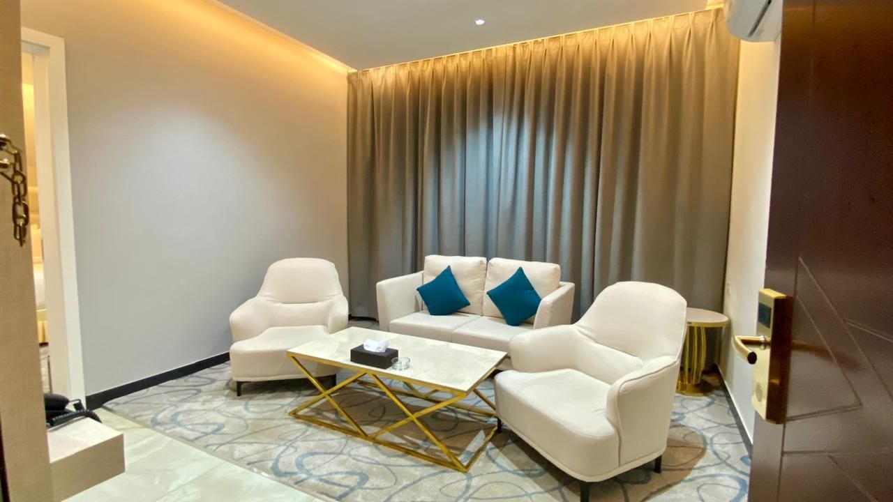 Uma sala de estar moderna com um sofá, uma mesa de centro e uma janela grande com cortinas.