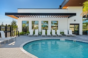 Uma área de piscina moderna com piscina transparente, cadeiras de descanso brancas e uma estrutura de pérgola.