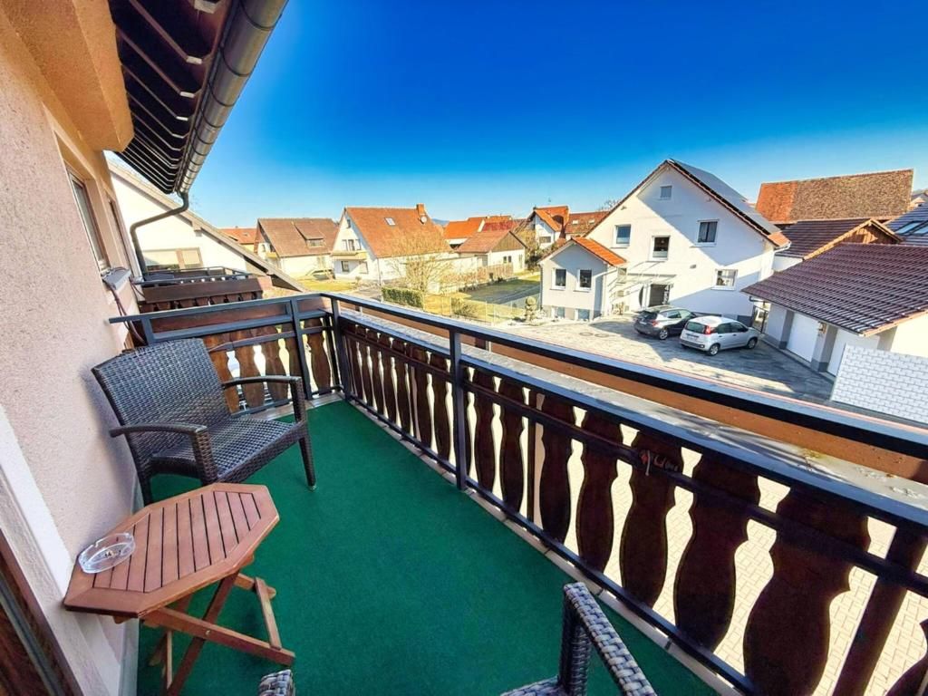 Varanda com chão verde, móveis de vime e vista para as casas vizinhas.