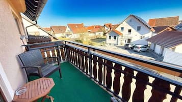 Varanda com chão verde, móveis de vime e vista para as casas vizinhas.