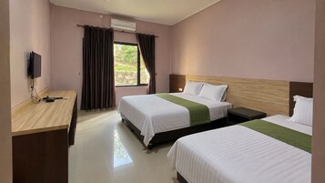 Quarto de hotel com duas camas, uma escrivaninha e um ar condicionado.