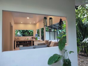 Cozinha moderna com ilha integrada, área de refeições com banco e vista para vegetação exuberante.