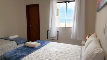 Quarto com duas camas, janela com vista para a praia e porta com design exclusivo.
