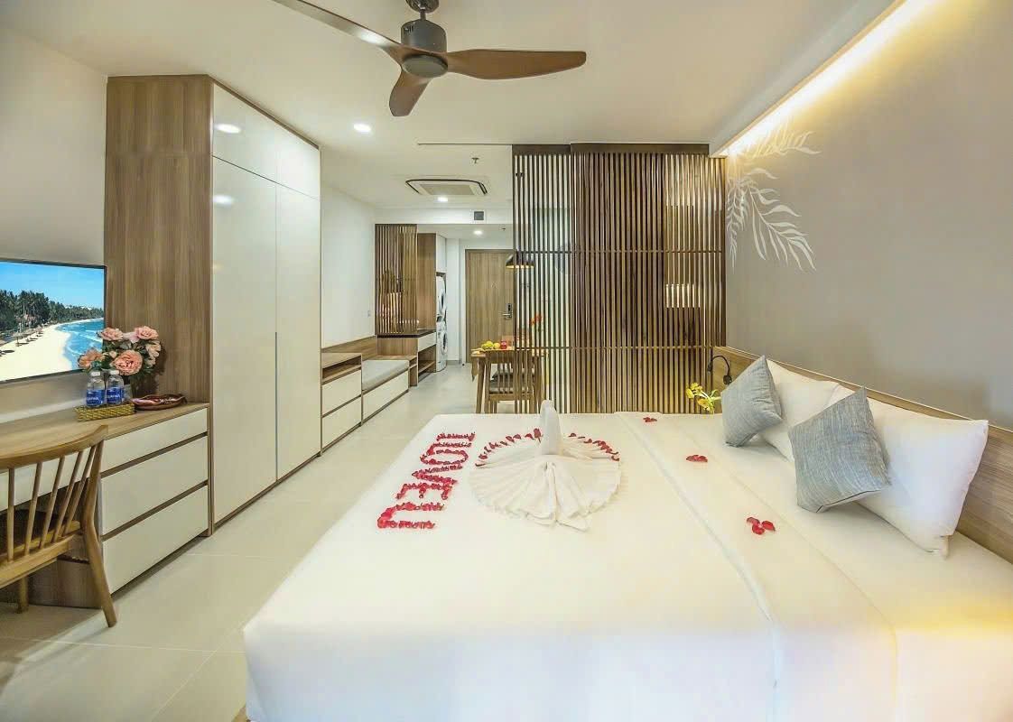 Quarto de hotel moderno com cama, escrivaninha e televisão.