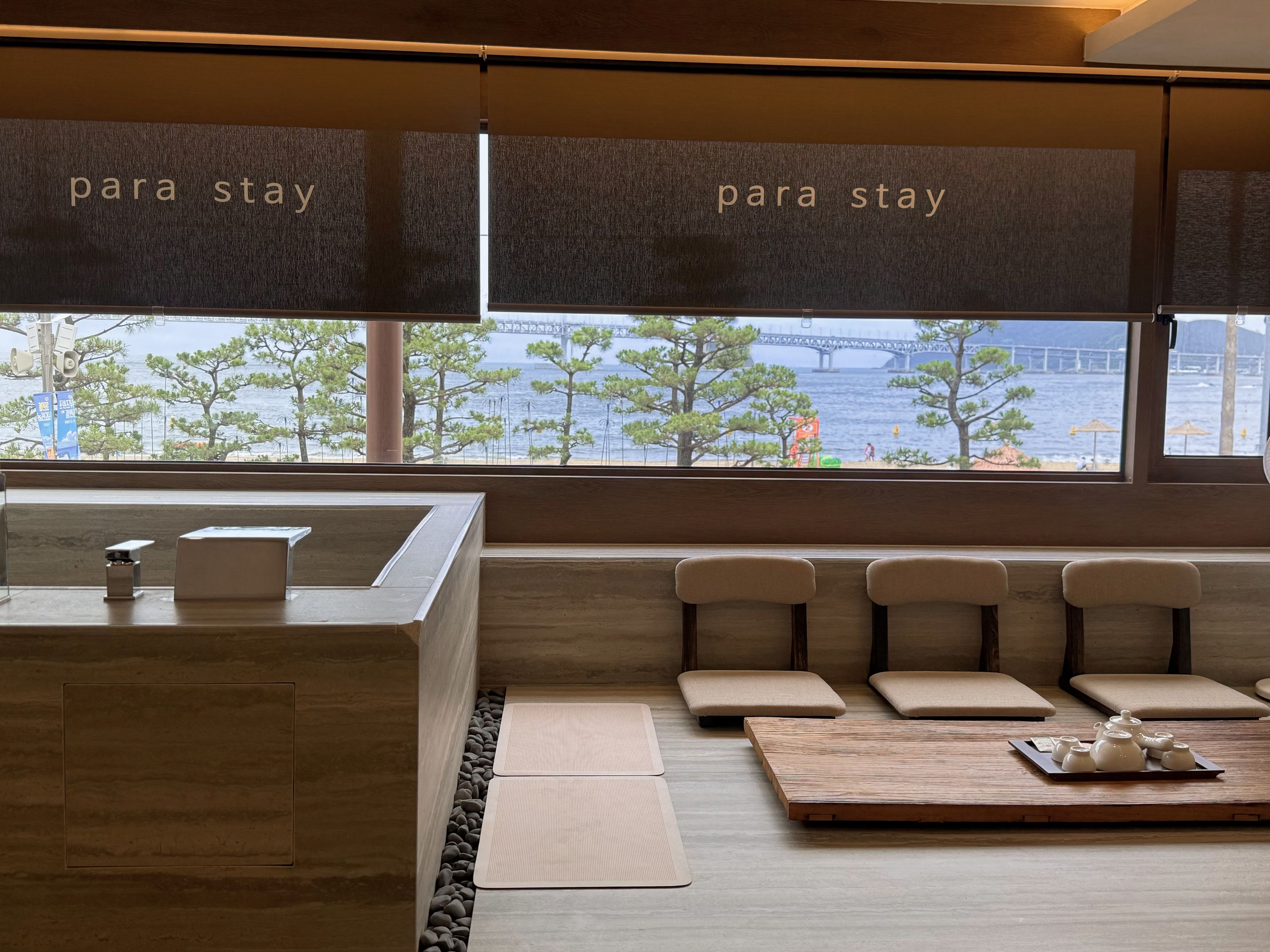 Quarto de hotel com balcão de recepção, área de estar e vista para o mar.