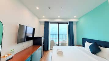 Quarto de hotel com cama, escrivaninha, televisão e varanda com vista.