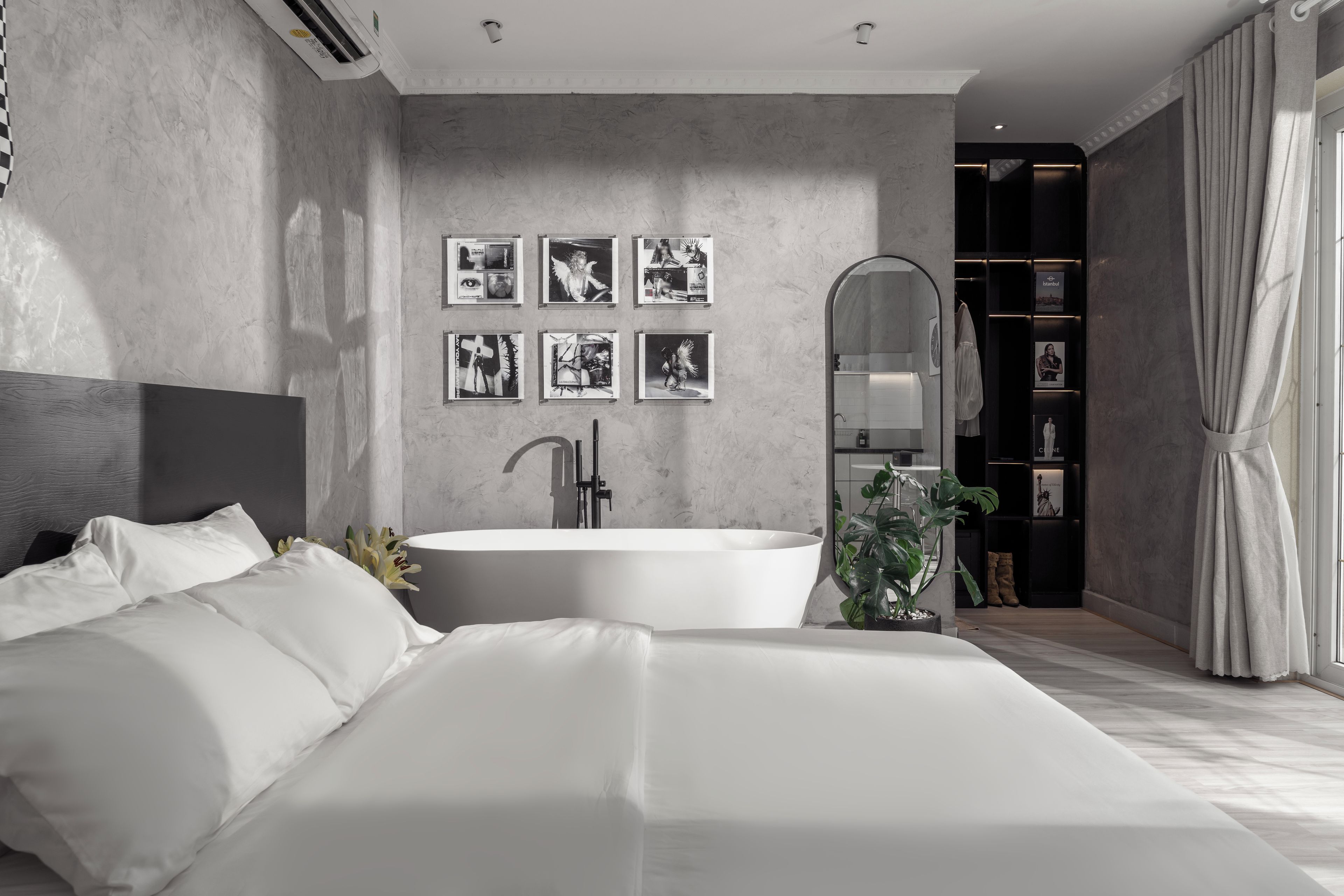 Quarto moderno com cama grande, banheira independente e espelho fixado na parede.