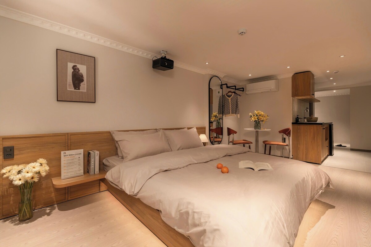 Quarto moderno com uma cama grande, mesas de cabeceira, um espelho e um guarda-roupa.