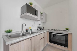 Uma cozinha moderna com micro-ondas embutido, pia dupla e fogão a gás.