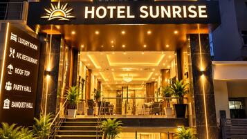 Entrada de hotel com uma placa indicando 'HOTEL SUNRISE'.