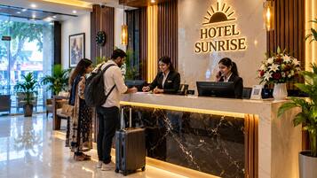 Balcão de recepção de hotel com bancada de mármore, um relógio e uma placa com a inscrição 'HOTEL SUNRISE'.