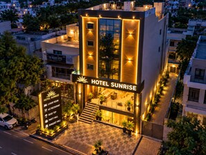 Um hotel moderno com uma placa visível, entrada xadrez e escadaria que leva ao saguão.
