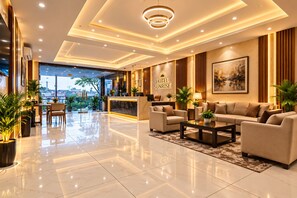 Um saguão de hotel com balcão de recepção, área de estar e vista para a paisagem urbana.