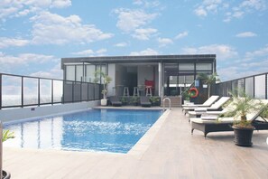 Área de piscina no terraço com espreguiçadeiras e plantas em vasos.