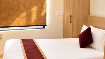 Quarto de hotel com cama, guarda-roupa e janela com cortina.