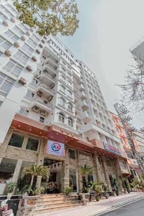 Um hotel com vários andares, entrada destacada, varandas e logotipo visível.