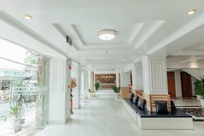 Um saguão de hotel com balcão de recepção, área de estar e escadaria.