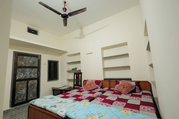 Quarto com cama, ventilador de teto, janela e prateleiras embutidas.
