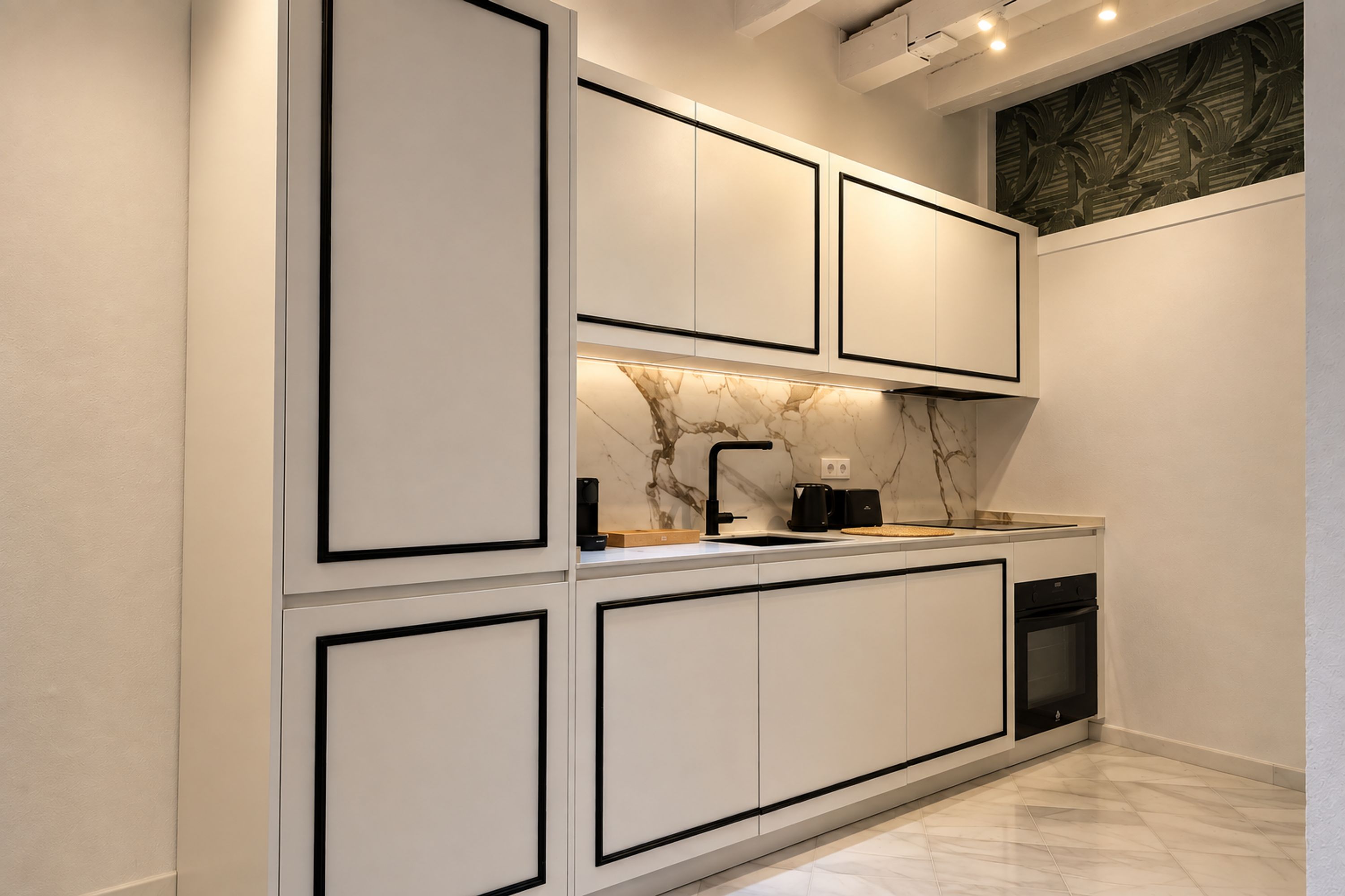 Cozinha moderna com armários brancos, painel de parede em mármore e torneira preta.