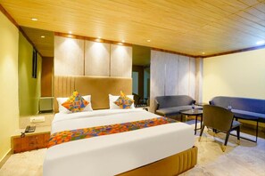 Quarto de hotel com uma cama grande, uma escrivaninha, duas cadeiras e um sofá.