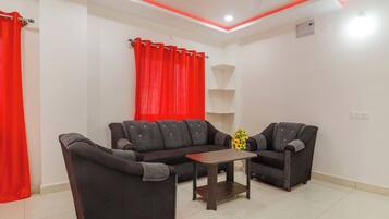 Sala de estar com sofá, duas poltronas, mesa de centro e cortina vermelha.