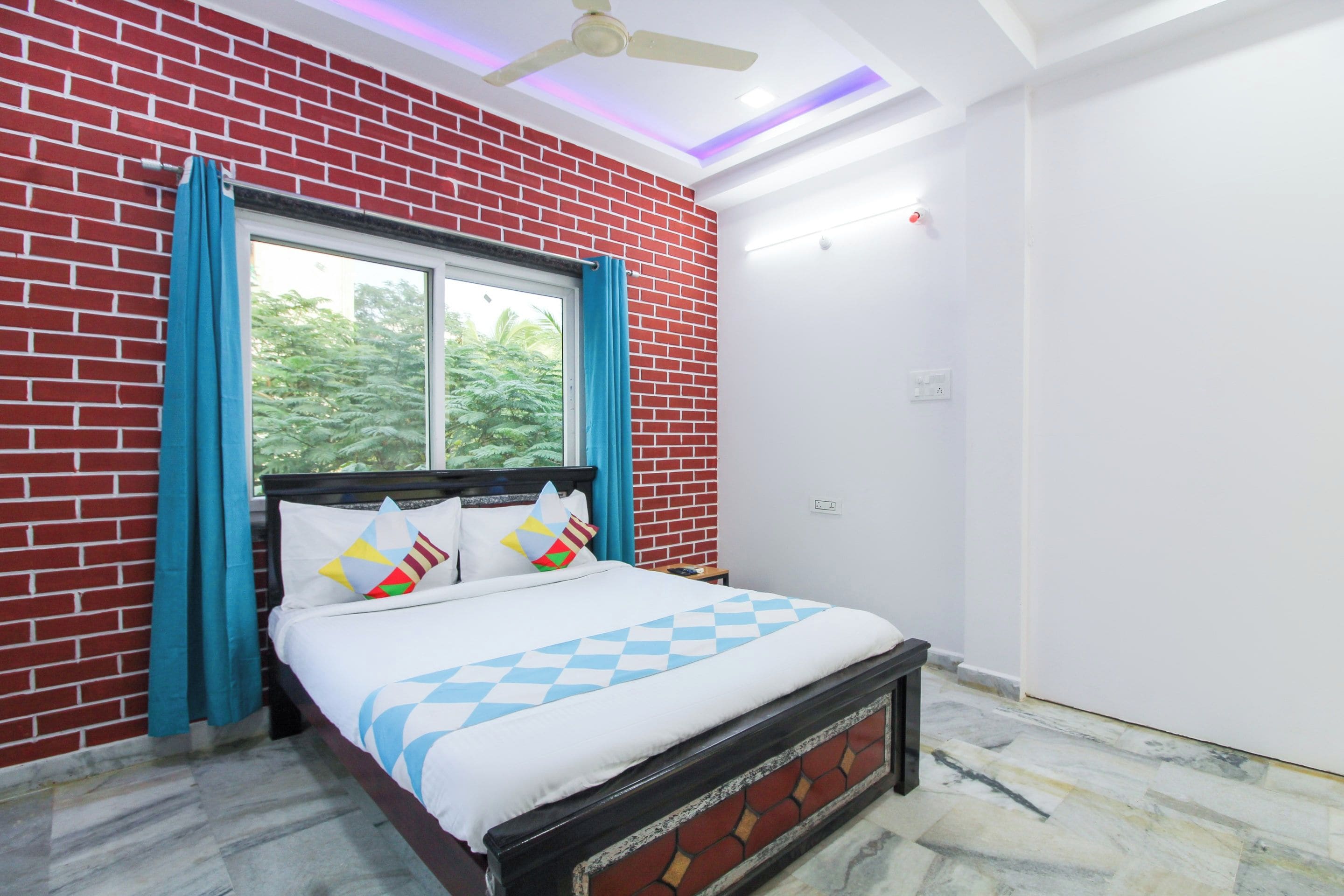 Quarto com cama, janela, ventilador de teto e porta.