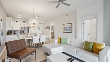 Uma sala de estar moderna com sofá, mesa de centro e um espaço de jantar com cadeiras e mesa.