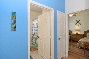 Quarto com cama de madeira, mesa de cabeceira, luminária e ventoinha no teto.