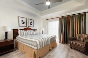 Quarto com cama, mesa de cabeceira, cadeira e cortinas.