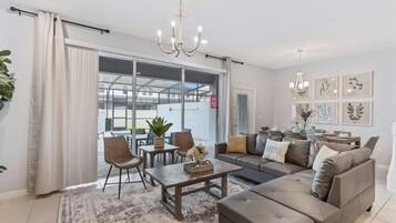 Uma sala de estar moderna com um sofá seccional, uma mesa de centro e um candelabro.