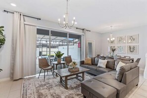 Uma sala de estar moderna com um sofá seccional, uma mesa de centro e um candelabro.