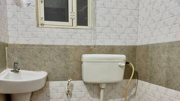 Casa de banho com sanita, lavatório e janela.