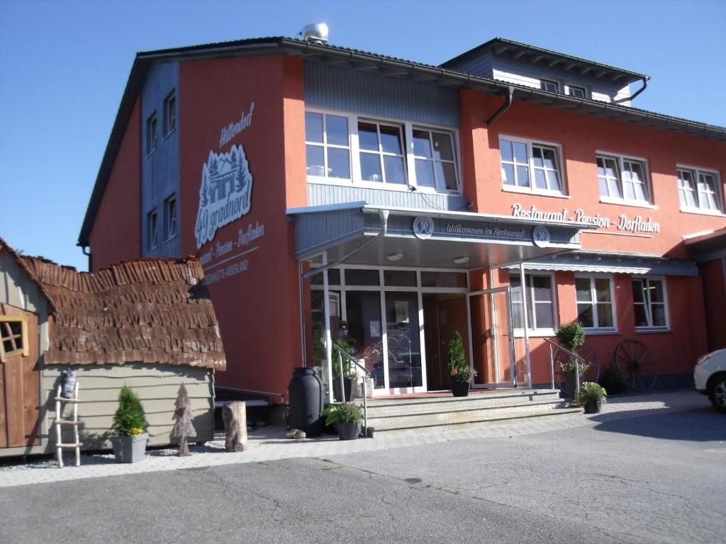 Um edifício com fachada vermelha, um letreiro que diz 'Restaurante' e uma pequena área externa com plantas.
