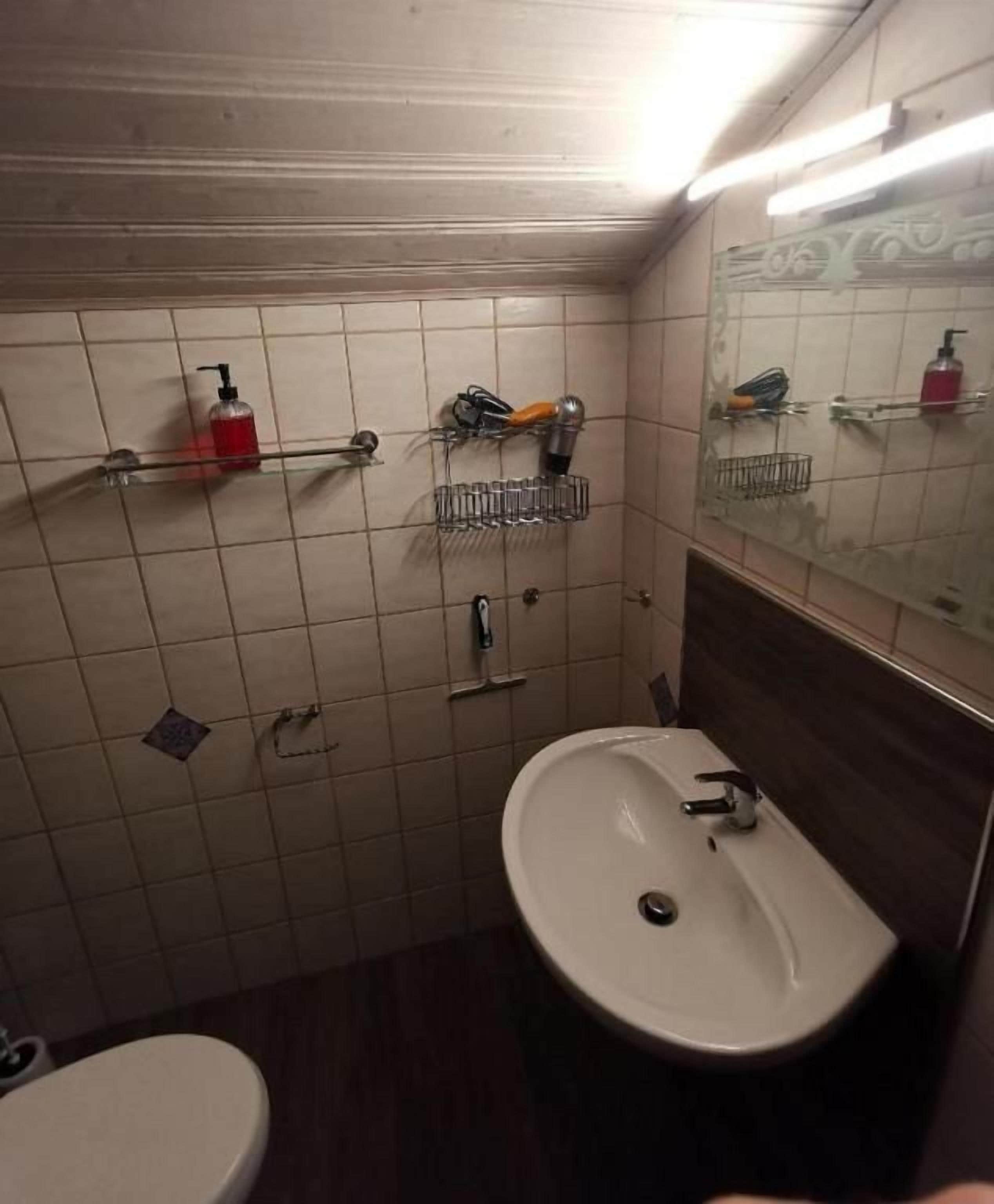 Casa de banho com lavatório, espelho e artigos de higiene em prateleiras.