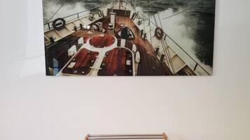 Pintura de um veleiro na parede, acima de um escorredor de metal.