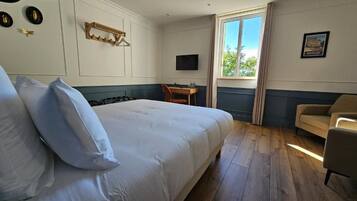 Quarto de hotel com uma cama grande, uma mesa, uma cadeira e uma televisão.