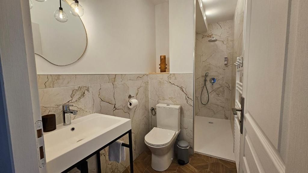 Casa de banho com lavatório, sanita e chuveiro, todos brancos.