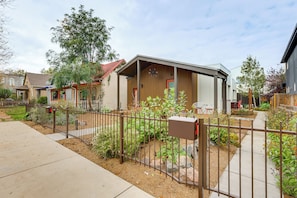 Um bairro residencial com fileira de casas, cerca de metal e jardim com diversas plantas.