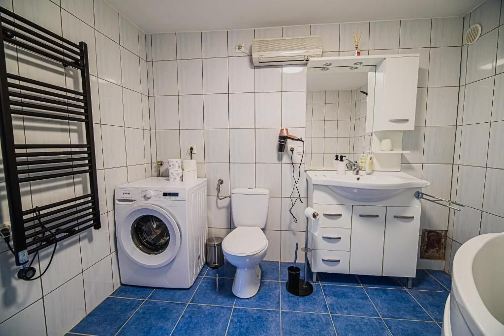 Casa de banho com máquina de lavar roupa, sanita, lavatório e banheira.