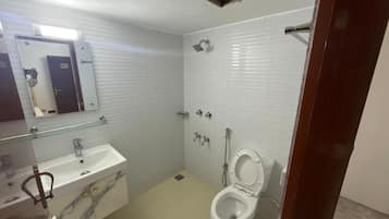 Casa de banho com lavatório branco, espelho e sanita.
