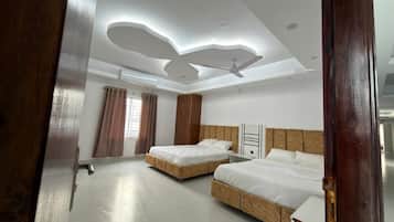 Quarto de hotel com duas camas, ventilador de teto e design moderno.