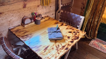 Uma mesa de jantar de madeira com uma cadeira de palha, um livro com uma pena e um objeto decorativo sobre a mesa.