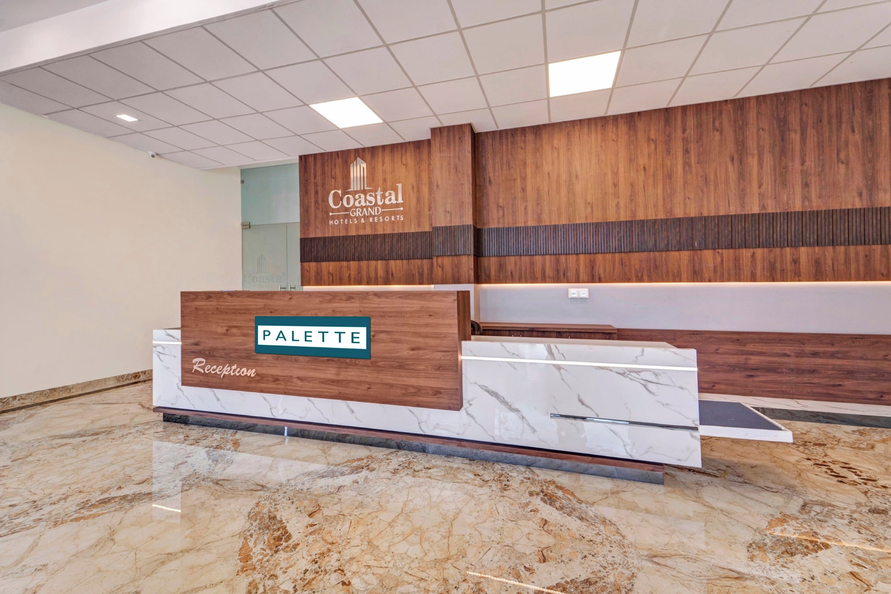 Bancada de recepção com painel de madeira e uma placa que diz 'Coastal Grand Hotels & Resorts'.