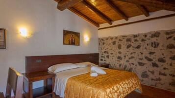 Um quarto com uma cama, uma escrivaninha de madeira e uma parede de pedra.