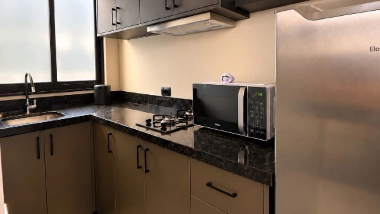 Cozinha com geladeira de aço inoxidável, micro-ondas e fogão a gás.