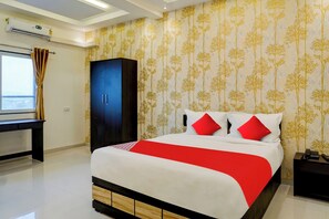 Quarto de hotel com cama, guarda-roupa, escrivaninha e janela.