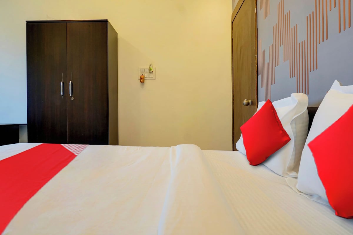 Quarto de hotel com cama, guarda-roupa e parede com padrão geométrico.
