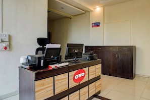 Bancada de recepção com logotipo, computador, impressora e telefone.