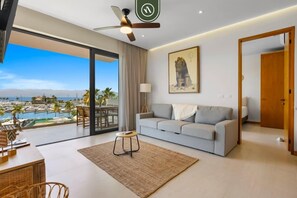 Uma sala de estar moderna com um sofá, uma mesa de centro e vista para uma piscina e montanhas.